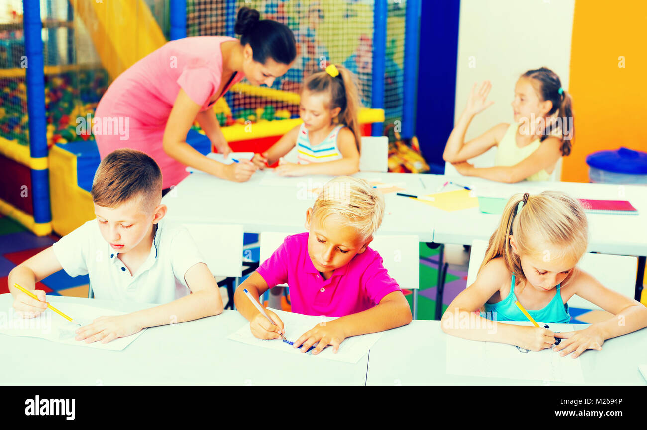 smiling american children sitting together and studying in class at ...