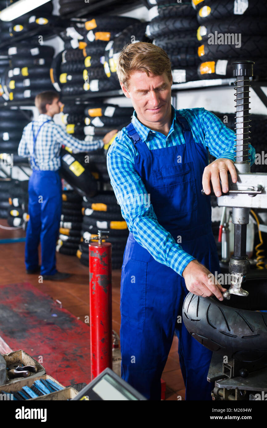 Portrait of positive man working with bike tires in tire shop Stock ...