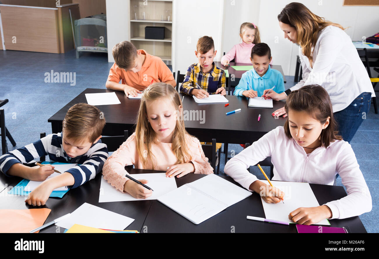 Positive boys and girls with teacher drawing in classroom Stock Photo ...