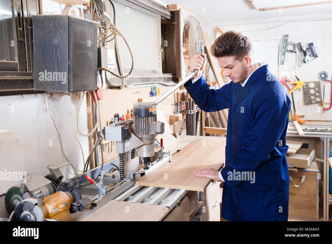Smiling working man preparing a chipboard for work at his workshop ...