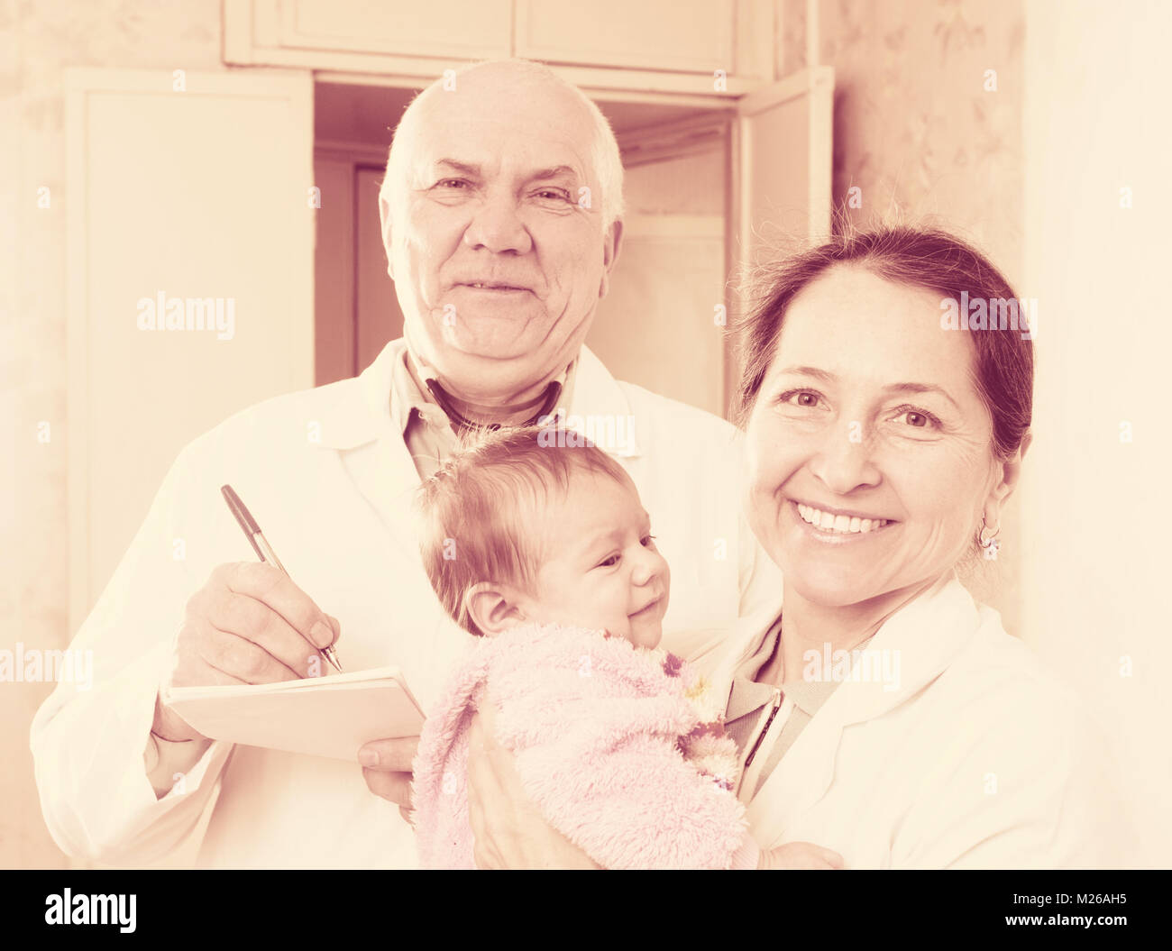 Portrait of Two pediatrician doctors with baby in interior Stock Photo ...