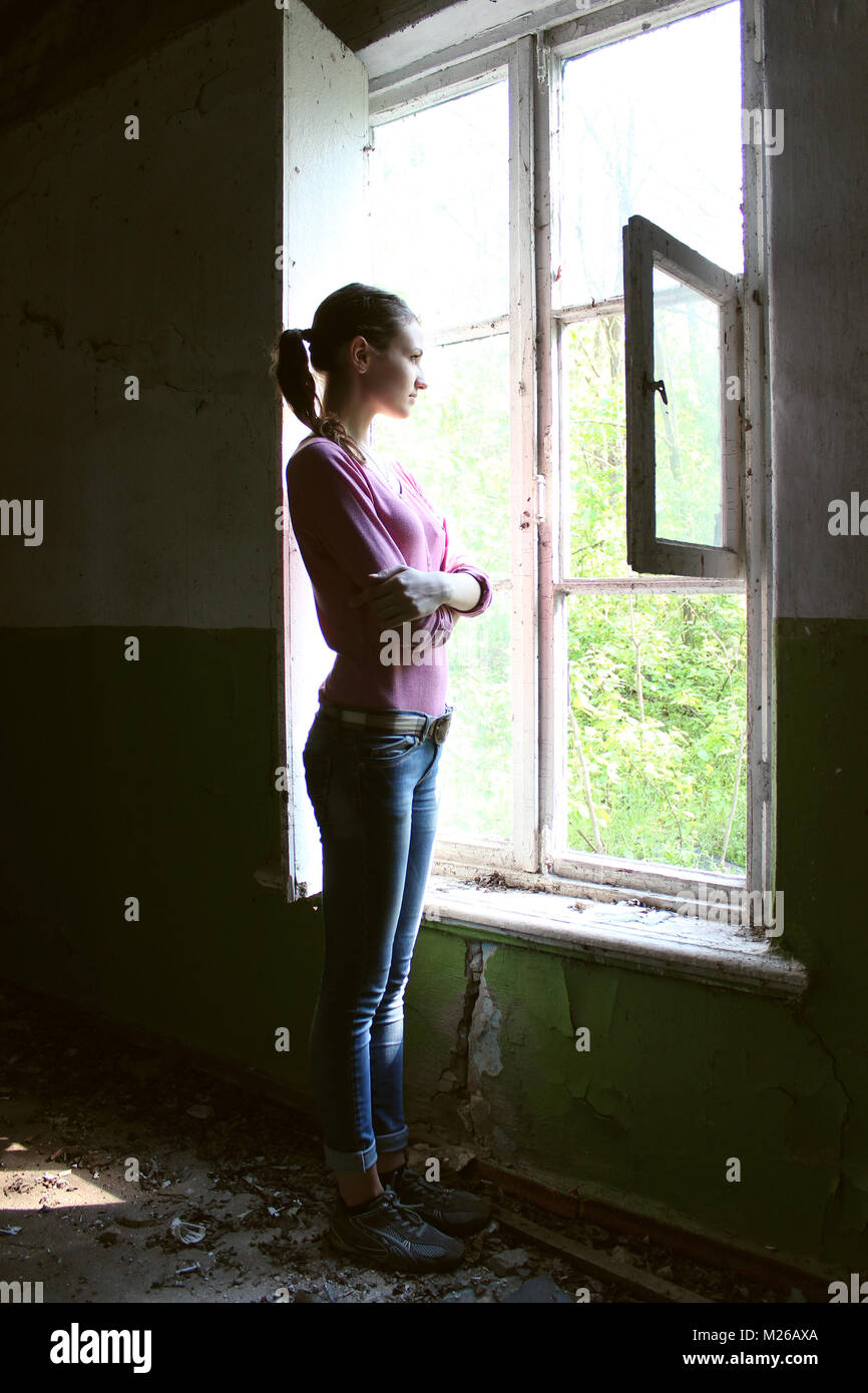 Beautiful girl looking through the old window Stock Photo - Alamy