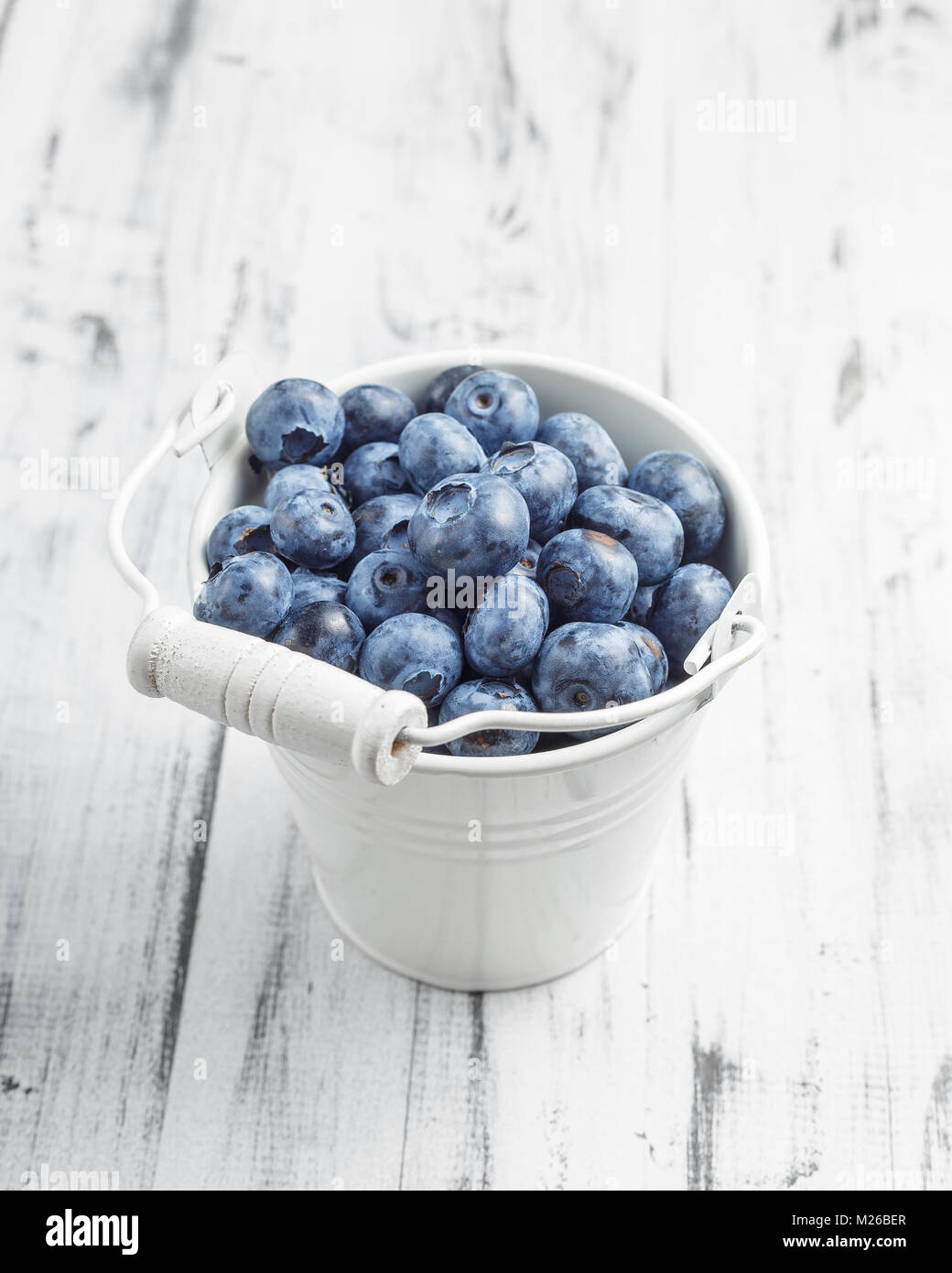 Blueberries in metal white bucket on white wooden background Stock ...