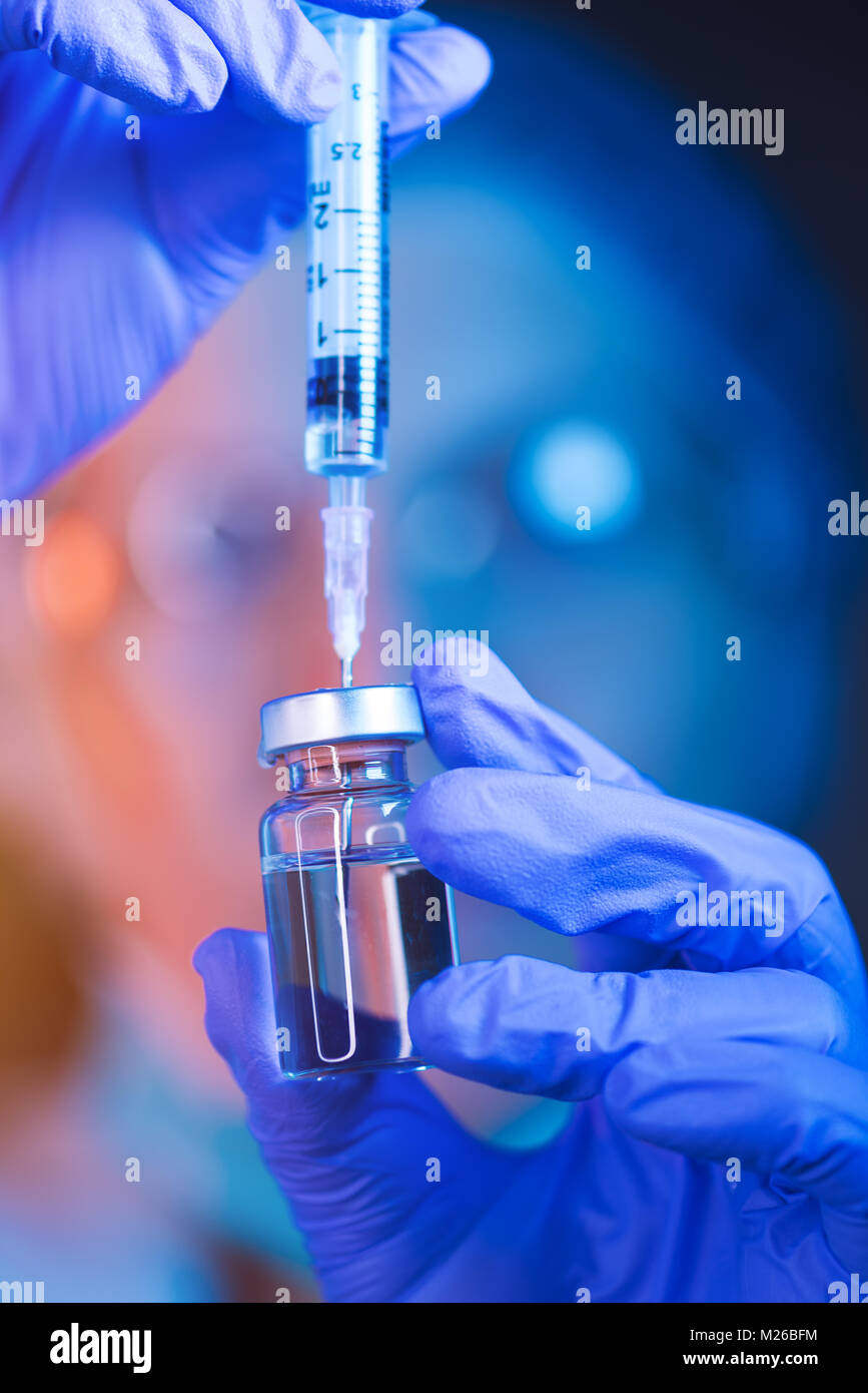 Doctor drawing up solution from vaccine bottle and filling syringe ...