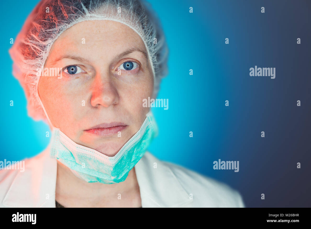 Portrait of female surgeon wearing protective surgical mask and looking ...