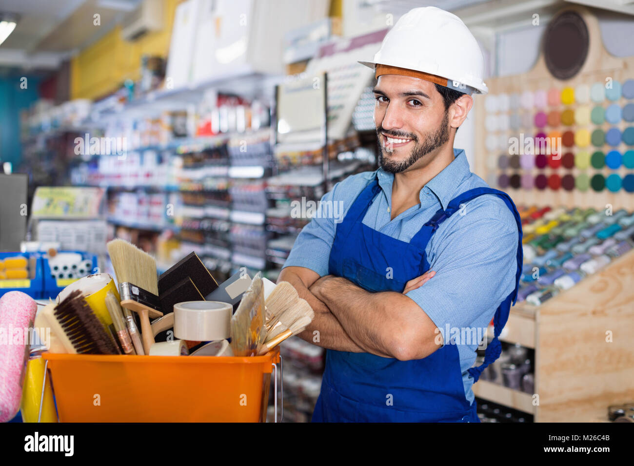 Happy positive smiling workman standing folded arms near basket with ...