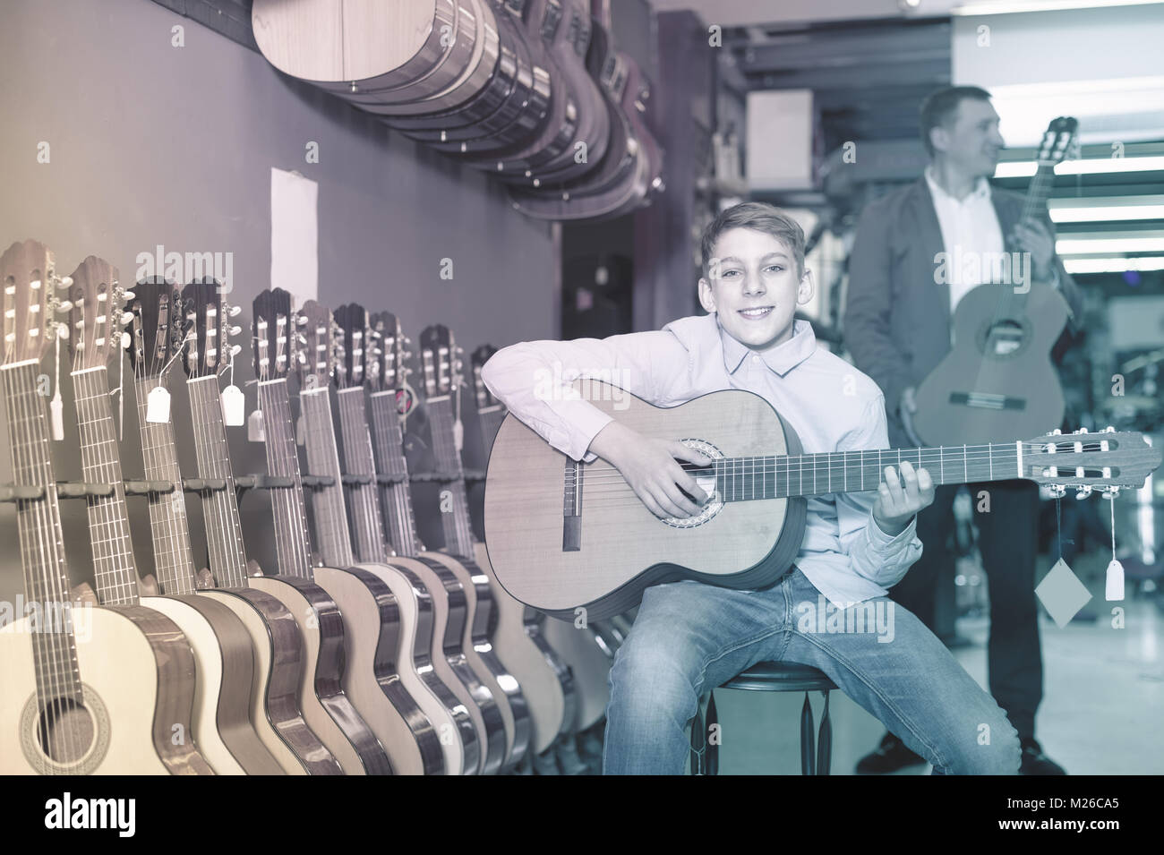 Smiling boy listening to guitar sound in music store Stock Photo - Alamy