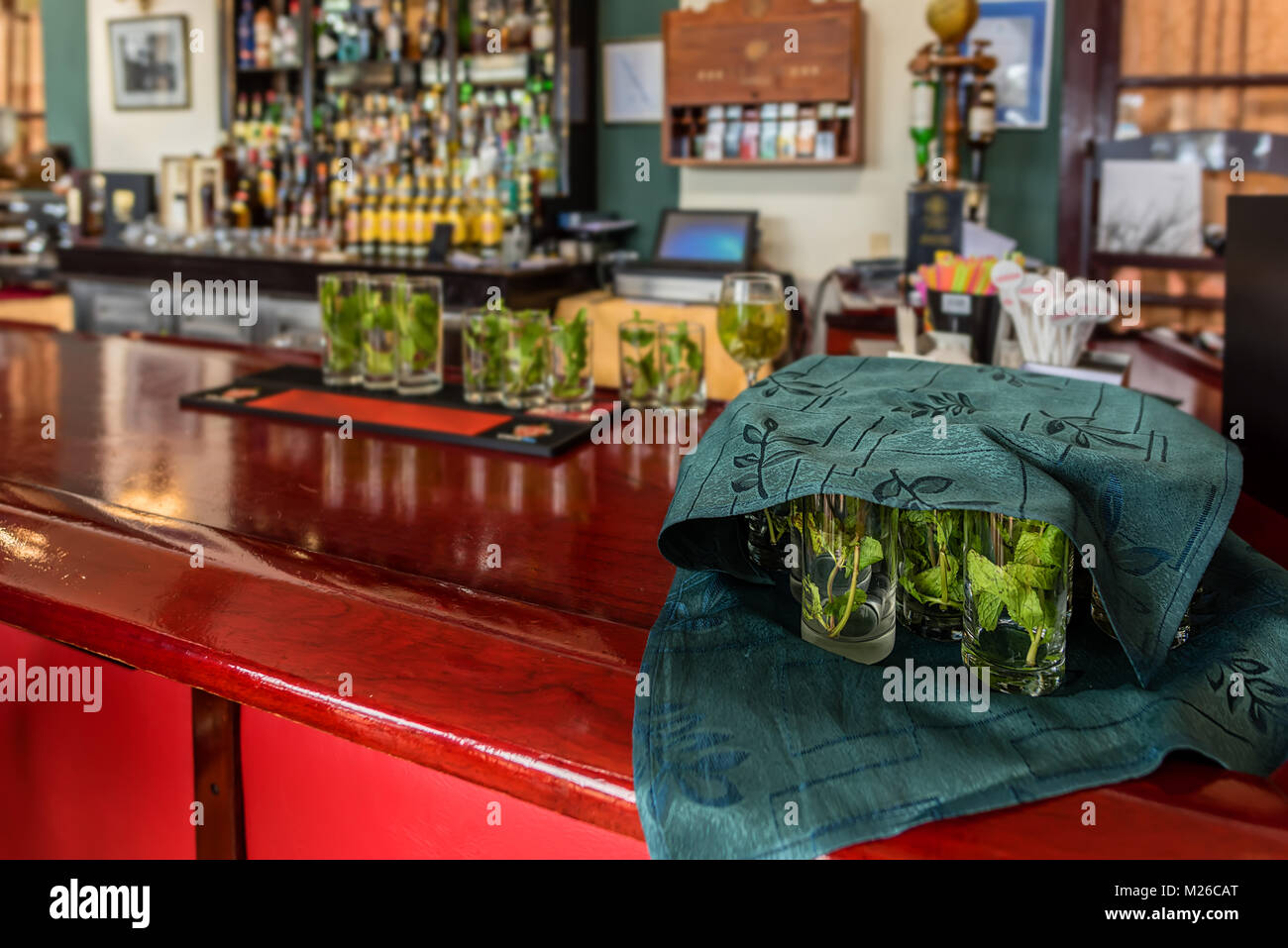 bar counter with mint plants in glasses covered with a green napkin and ...