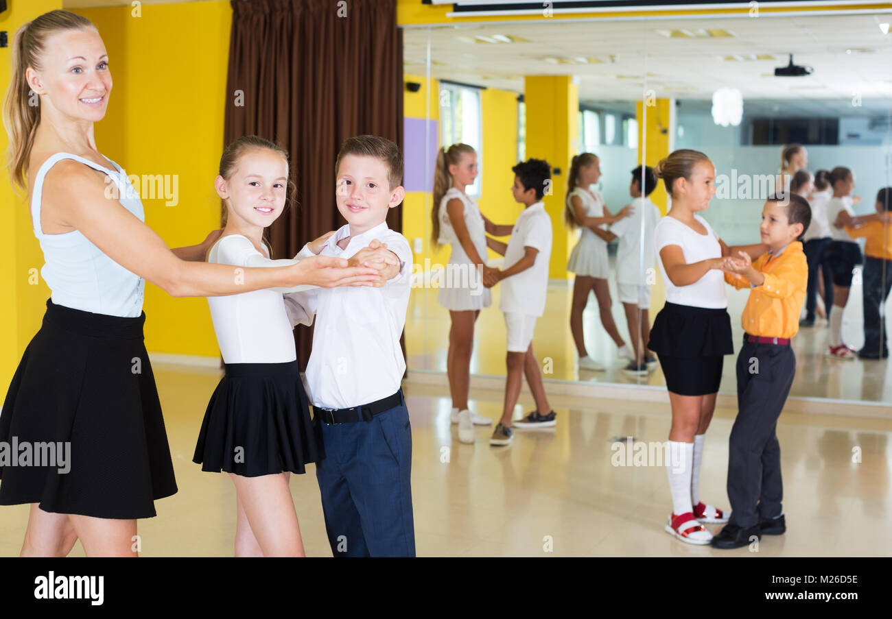 Children in dance hall examining new movements, smiling and having fun ...