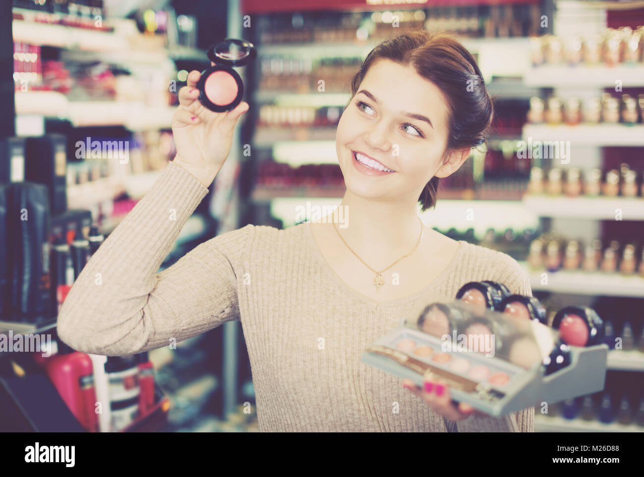 Glad female seller demonstrating assortment of cosmetics shop Stock ...