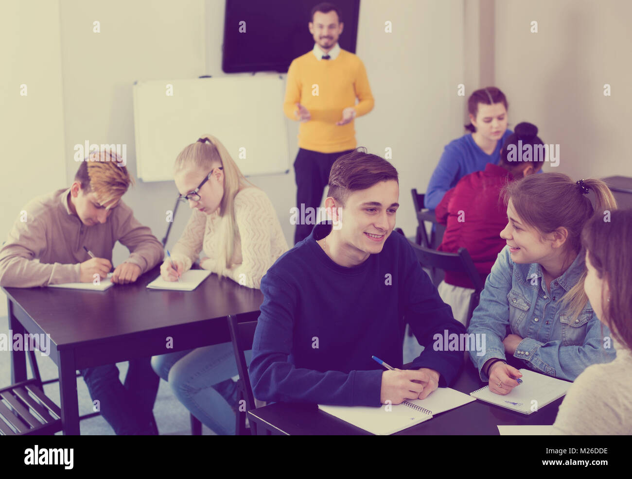 Cheerful classmates and teacher working in groups to complete task ...