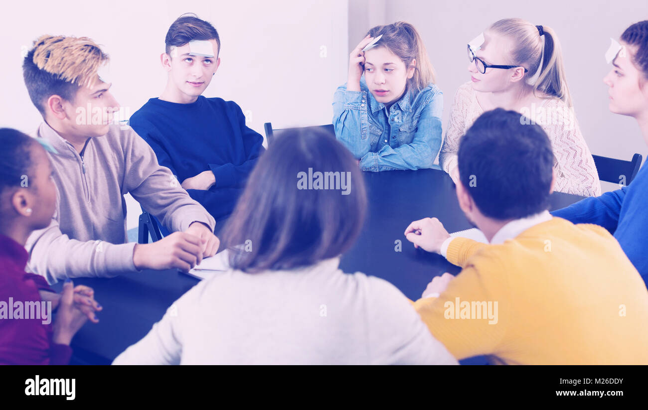 Male and female students playing guess-who game in school Stock Photo ...