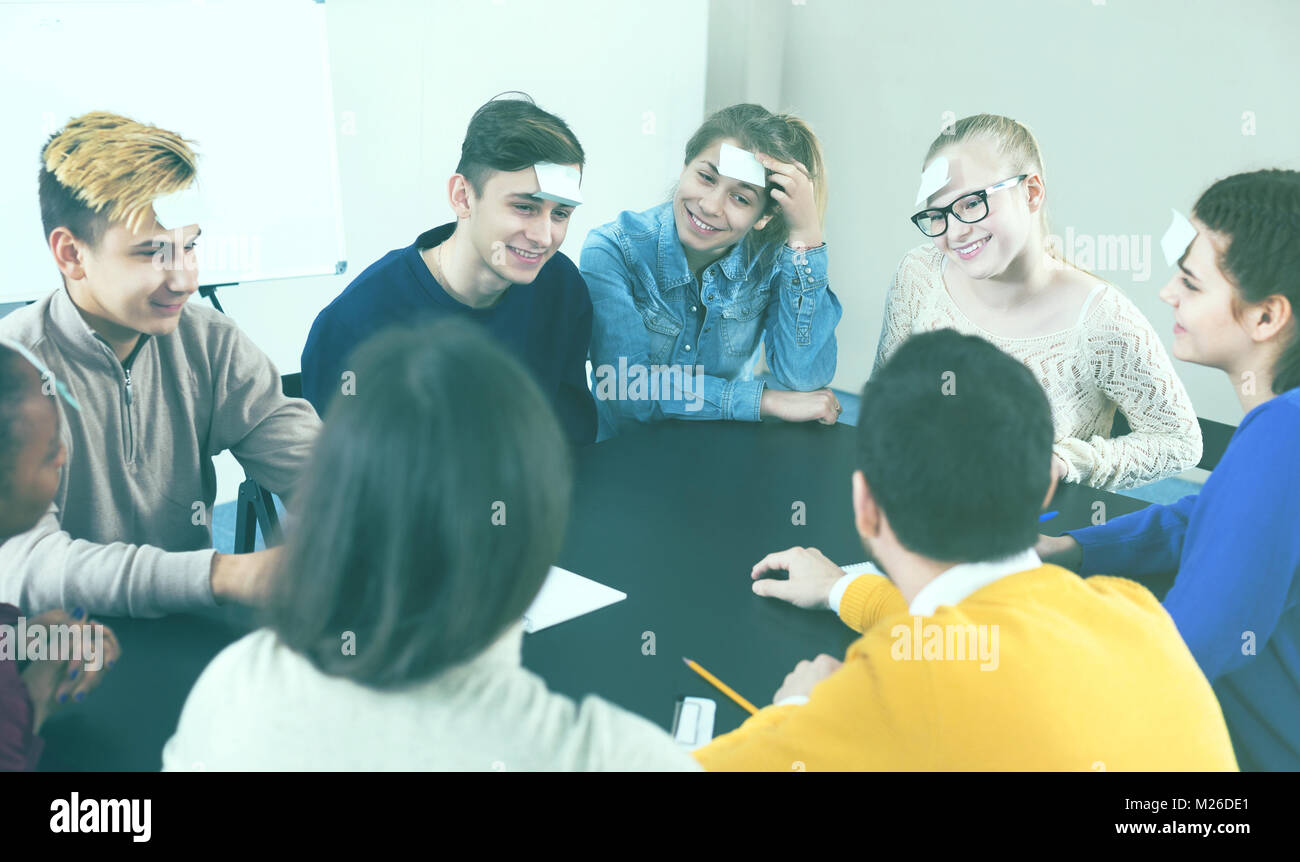 Positive young students playing guess-who game in school Stock Photo ...