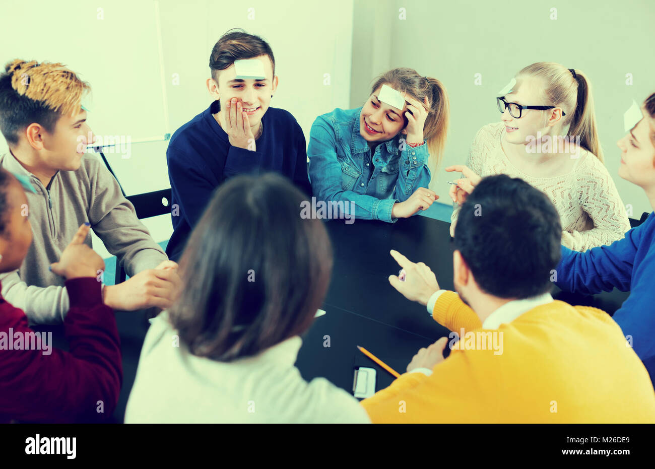 happy russian classmates having round of guess-who game during class ...