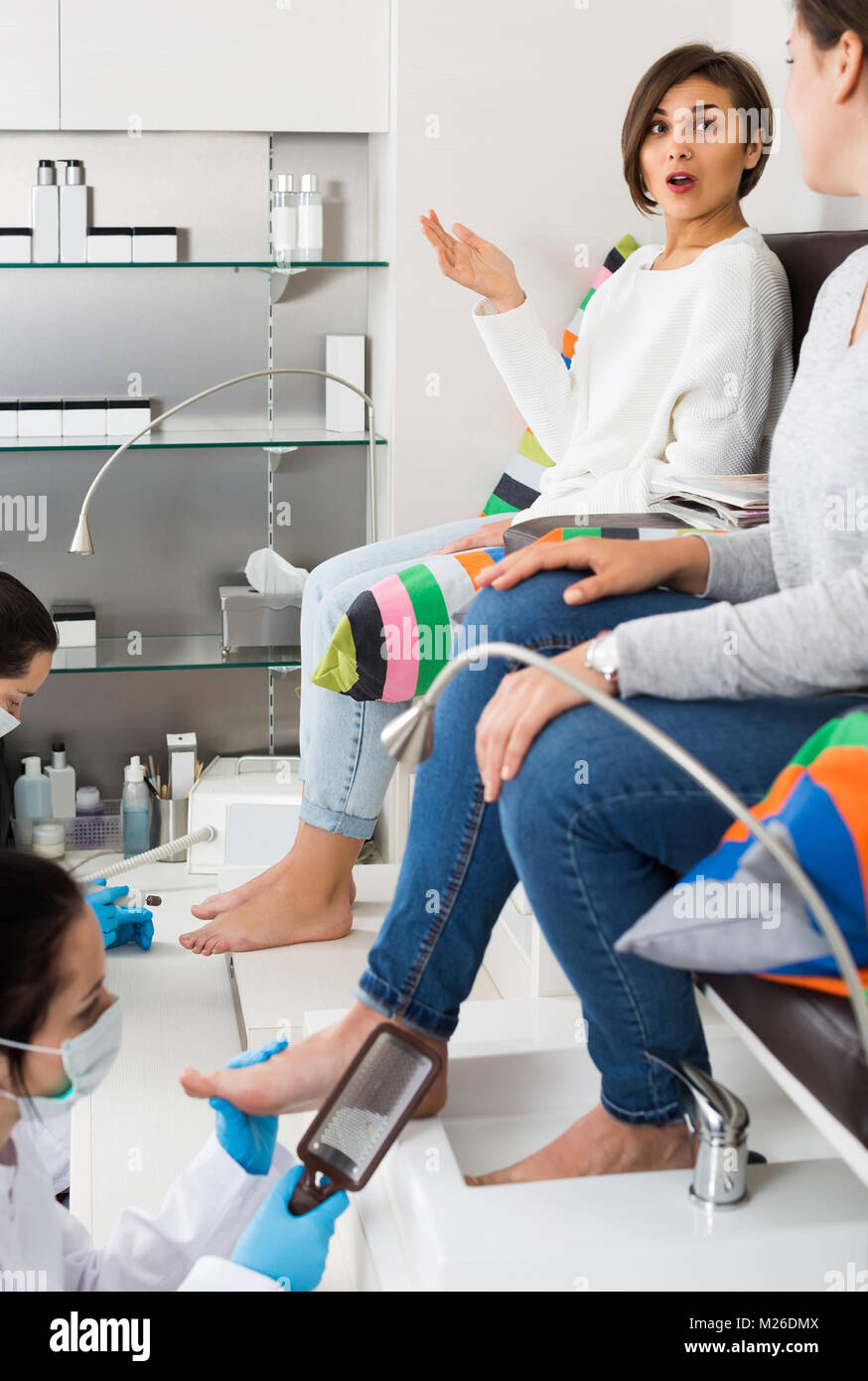Pair of happy french women clients getting pedicure in modern nail ...