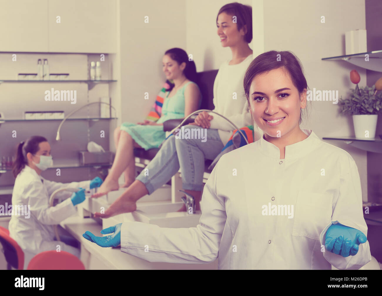 Portrait of happy professional nail master at working place inviting to ...
