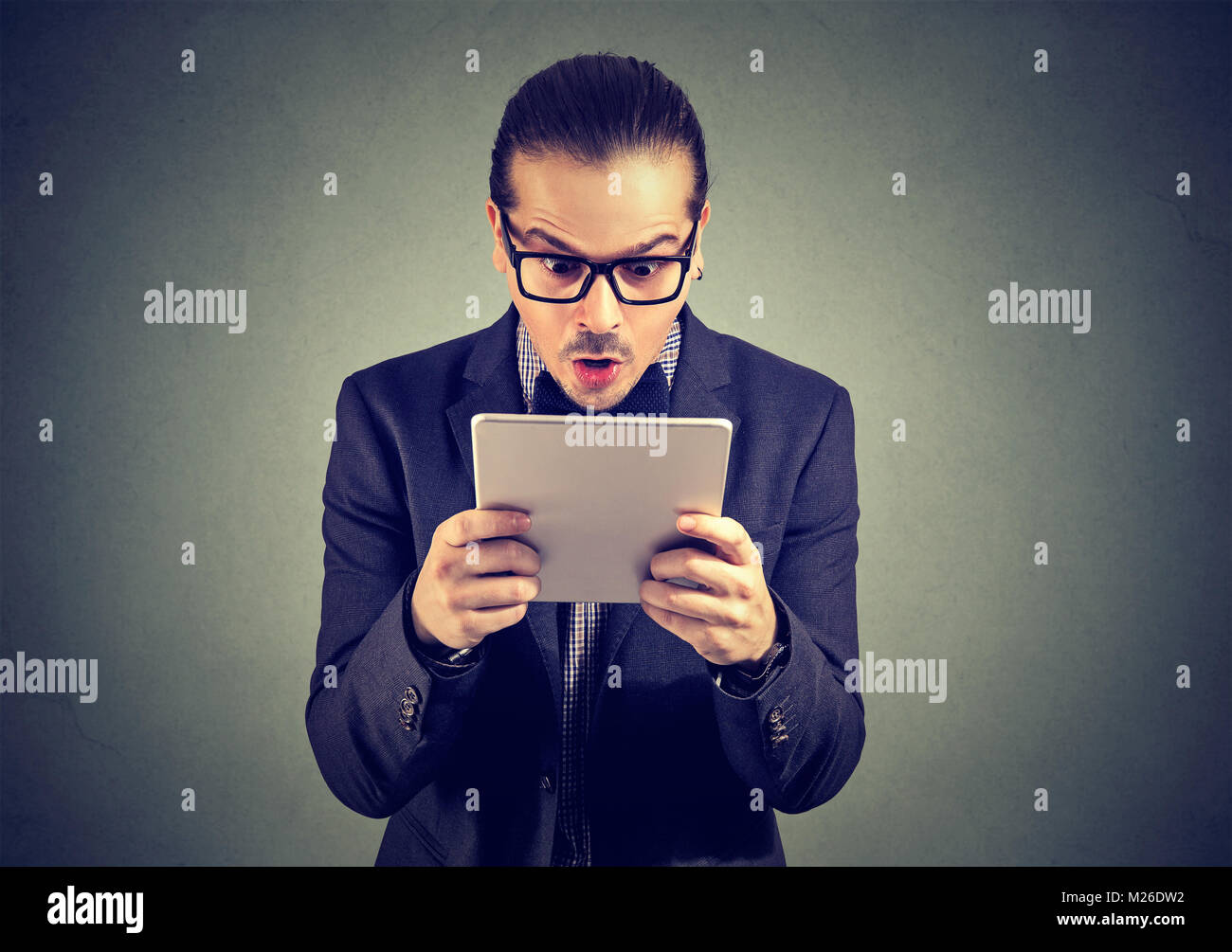 Formal man looking perplexed receiving news on tablet and posing on ...