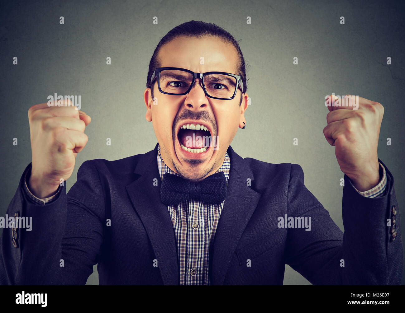 Young man in eyeglasses shouting expressively looking extremely mad ...