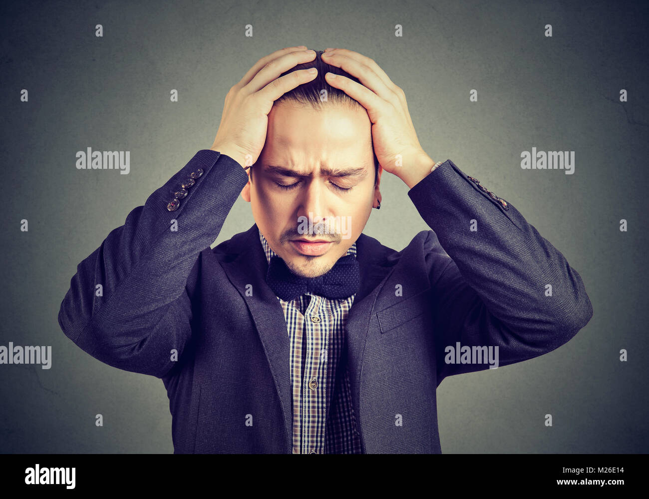 Young businessman in suit holding hands on head looking desperate Stock ...