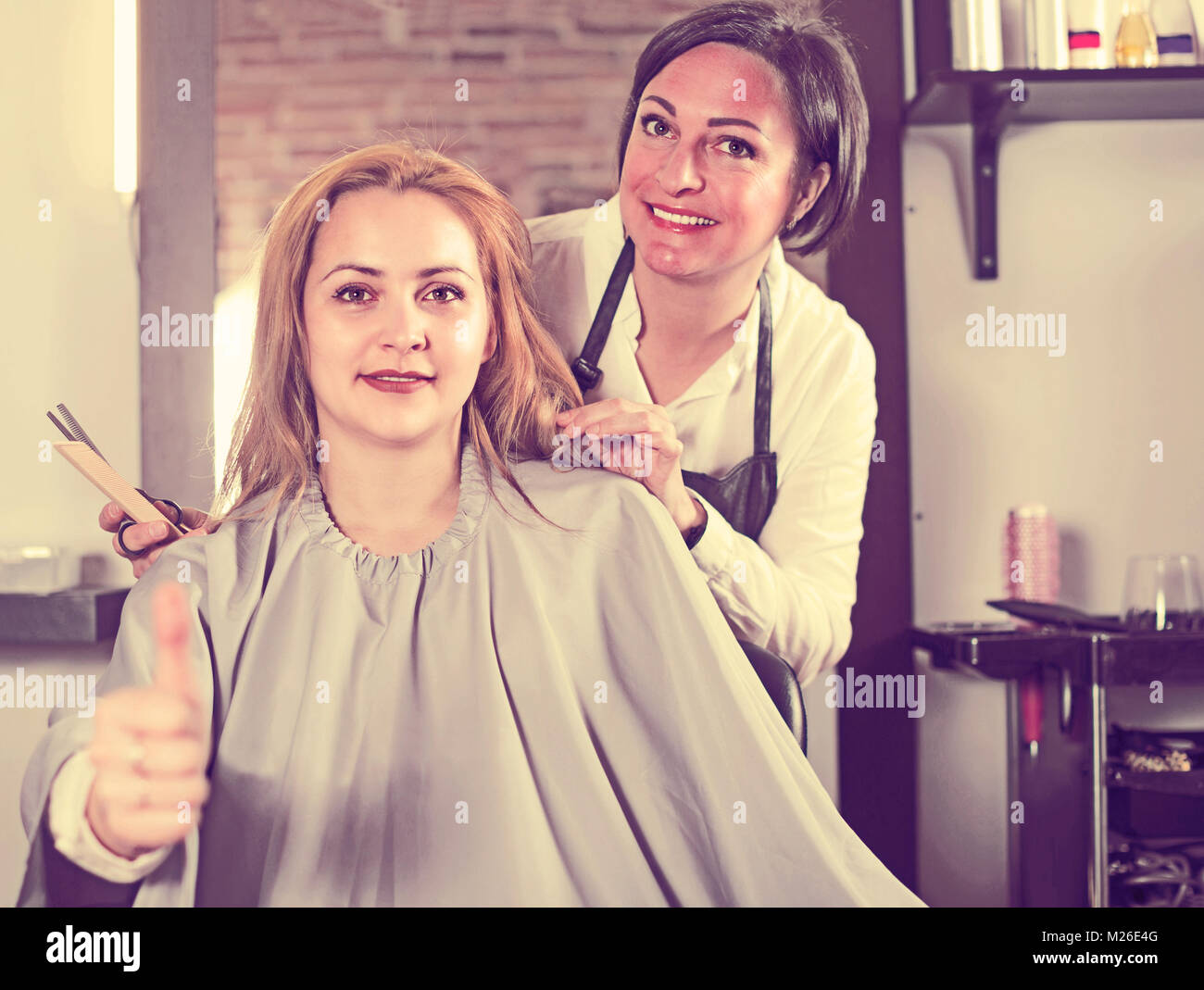 Young girl happy with her fashionable haircut and haircutter in ...