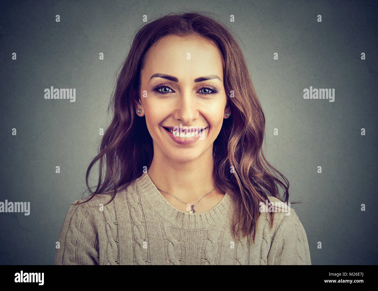 Beautiful ethnic model smiling at camera standing on gray backdrop ...