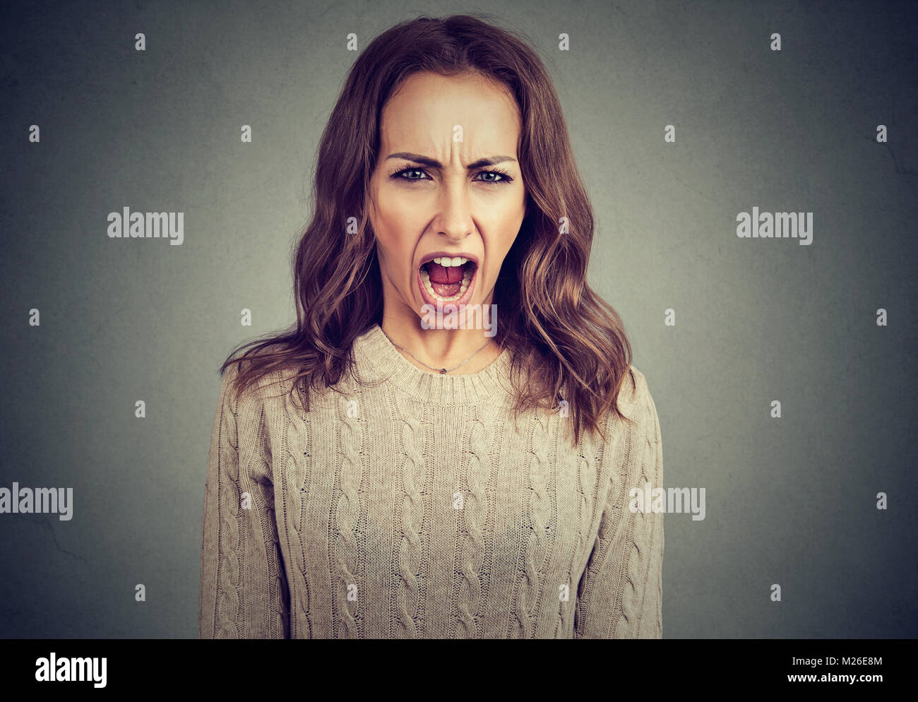 Young woman looking pissed off and yelling at camera on gray Stock ...