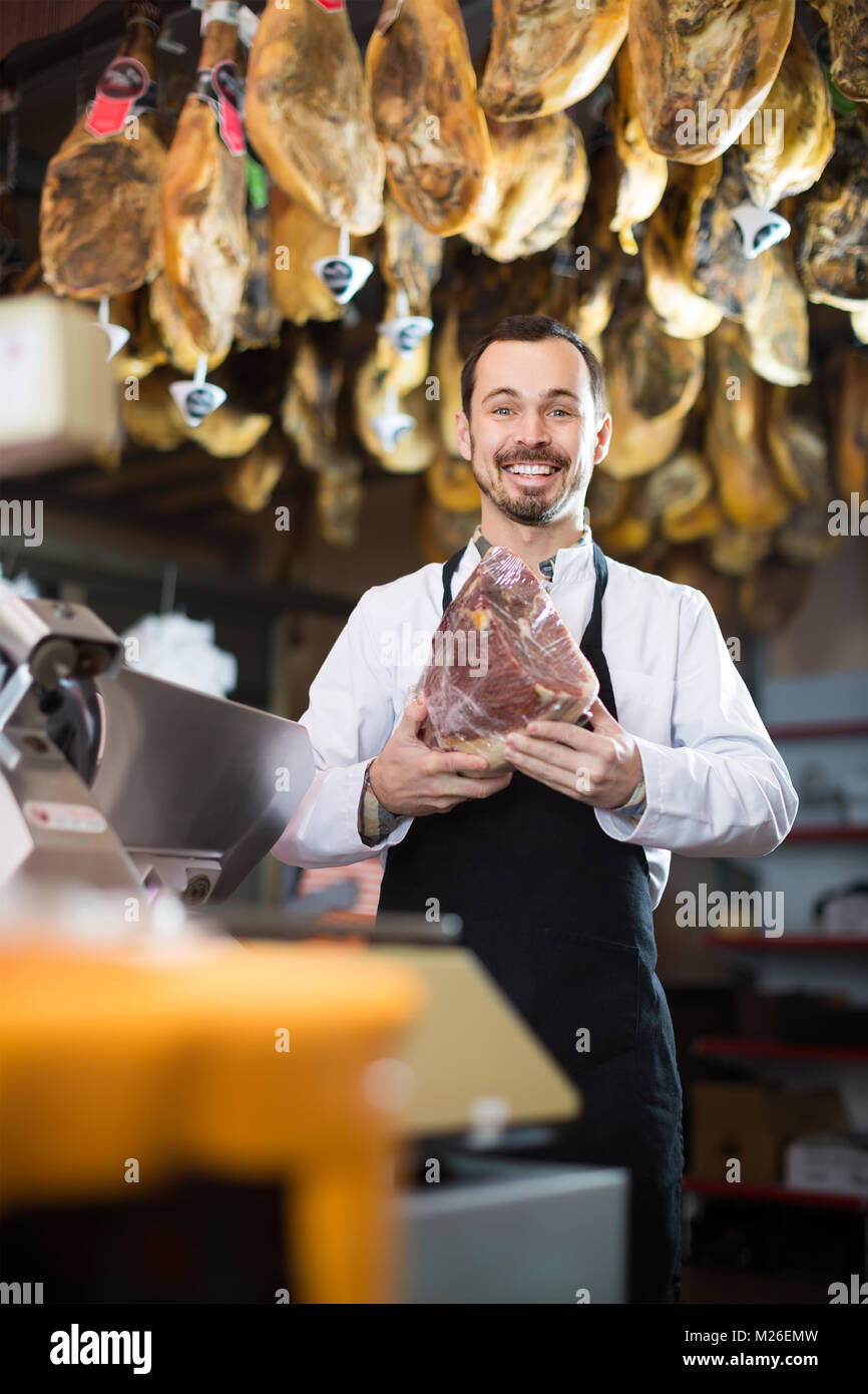 Cheerful Male Shop Assistant Using Scales For Piece Of Meat In Butcher