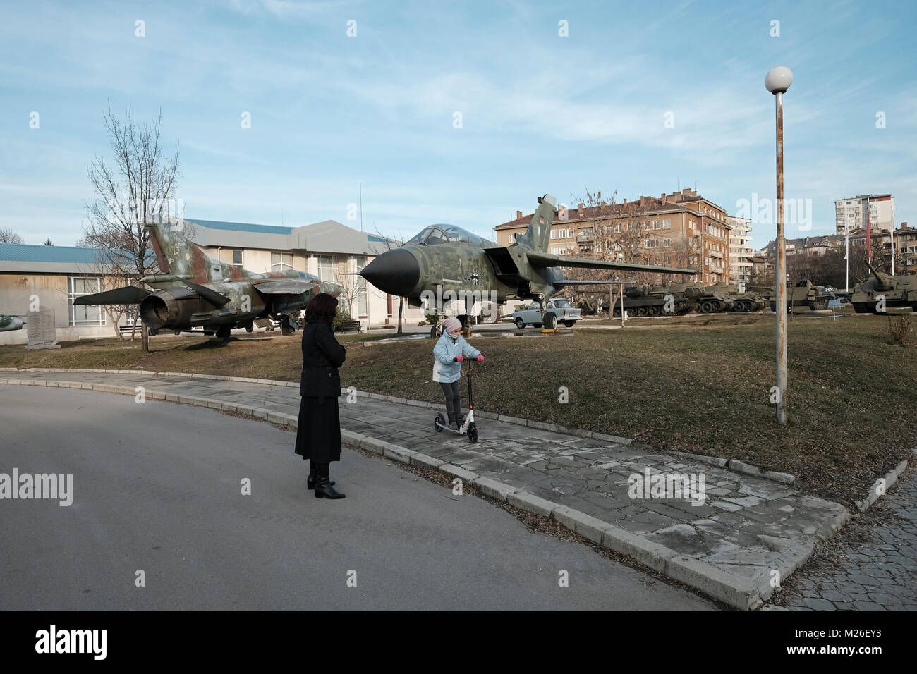A mother strolls with her daughter amid weaponry displayed at the ...