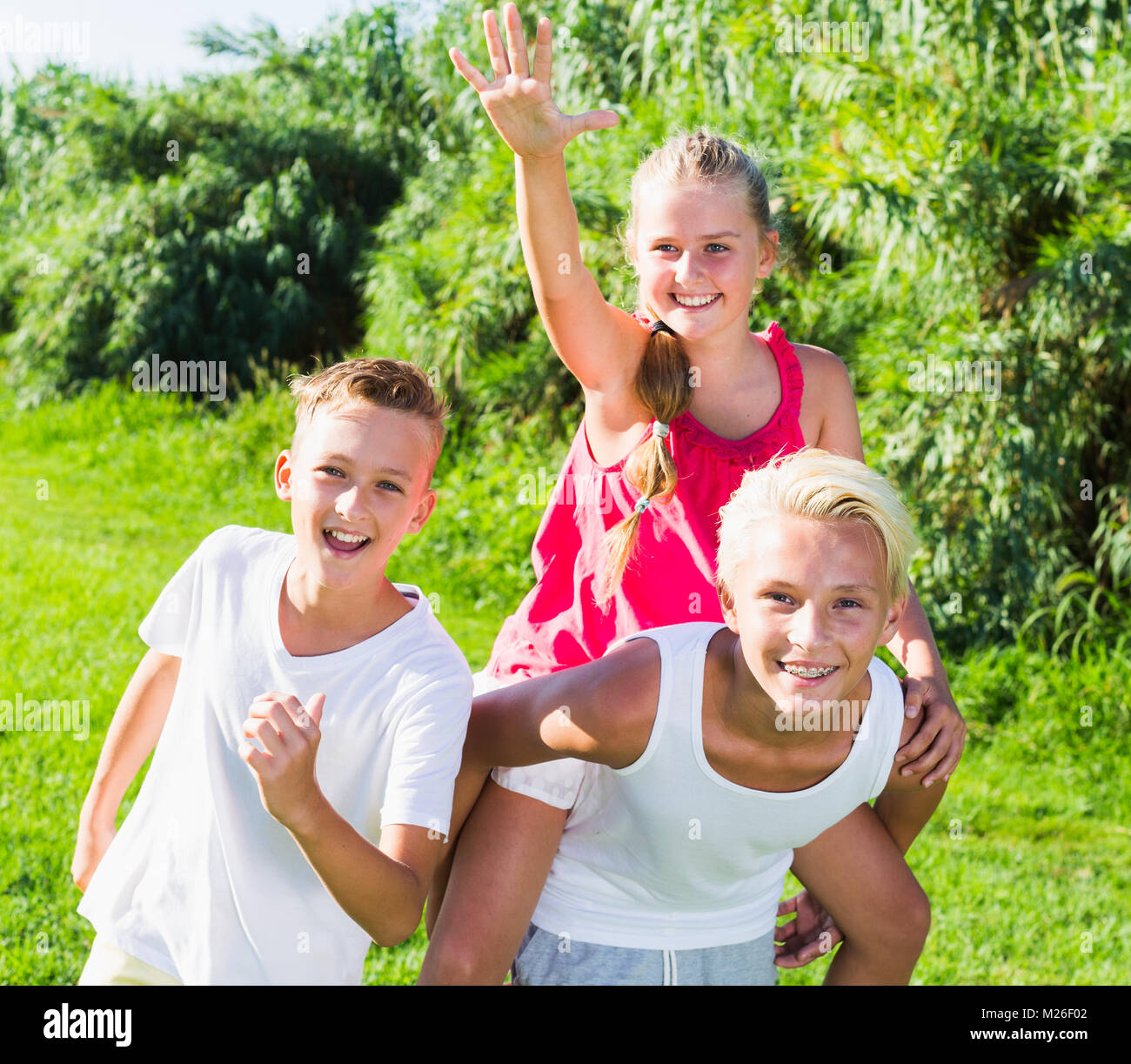 Happy children running together outdoors, boy carrying girl on back ...