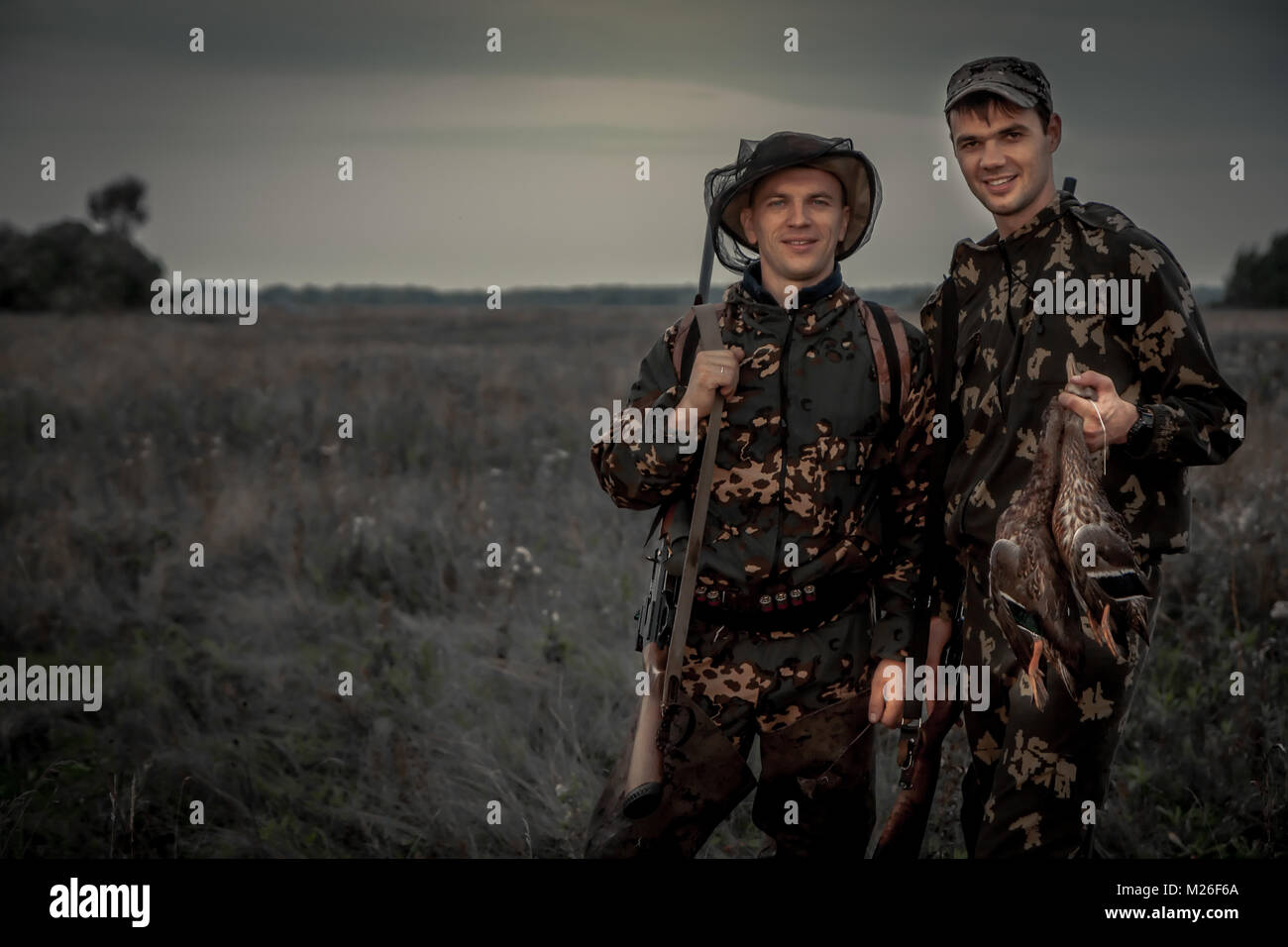Hunters men with trophy in rural field during hunting period at dusk ...