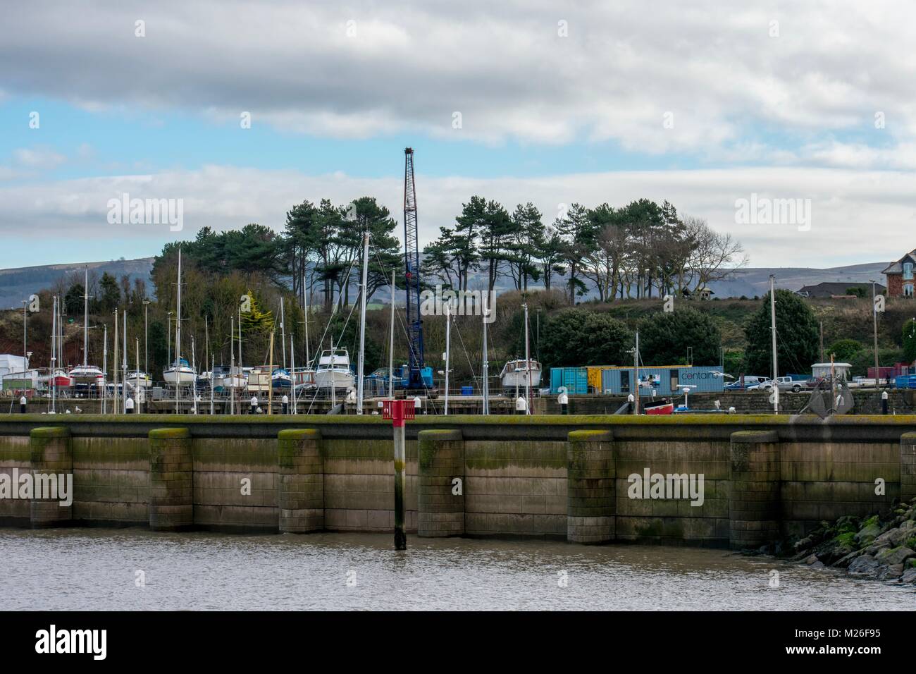 A view of the harbourside marina with boats out of water, trees and a ...