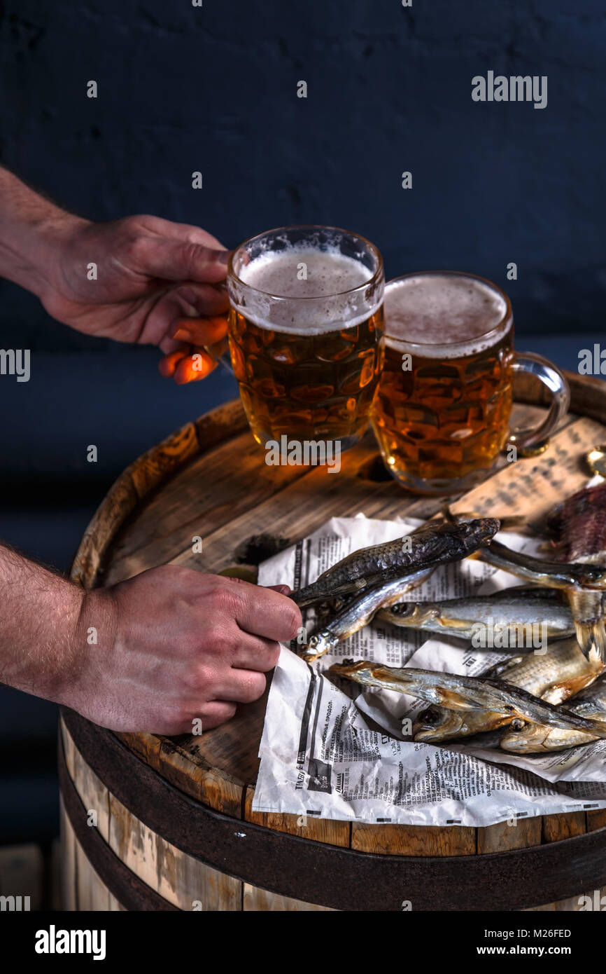 Man drink beer with dried fishes on a wooden barrel Stock Photo - Alamy