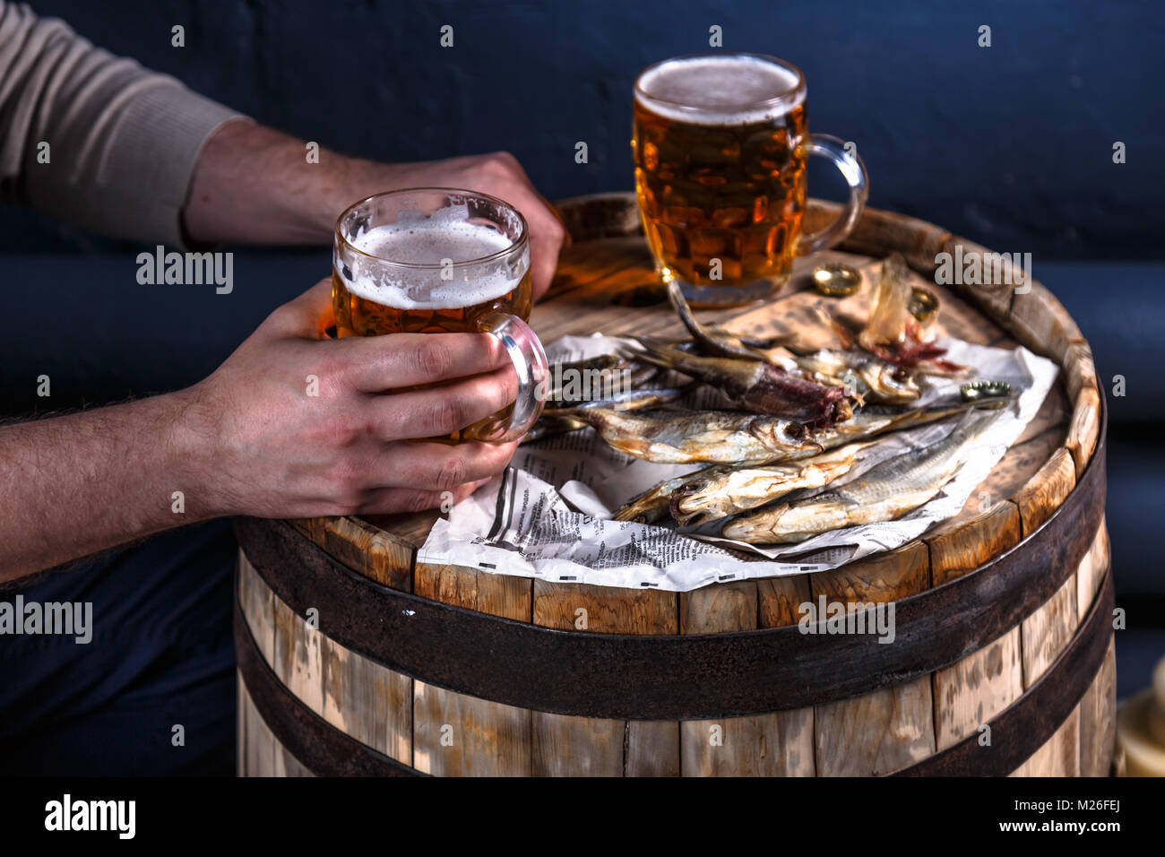 Man drink beer with dried fishes on a wooden barrel Stock Photo - Alamy