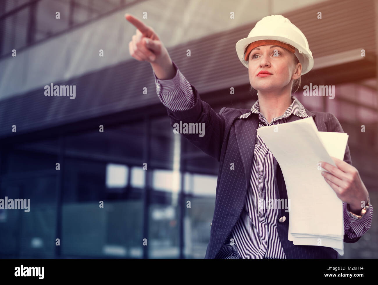 Professional woman in jacket and helmet pointing finger on object Stock ...