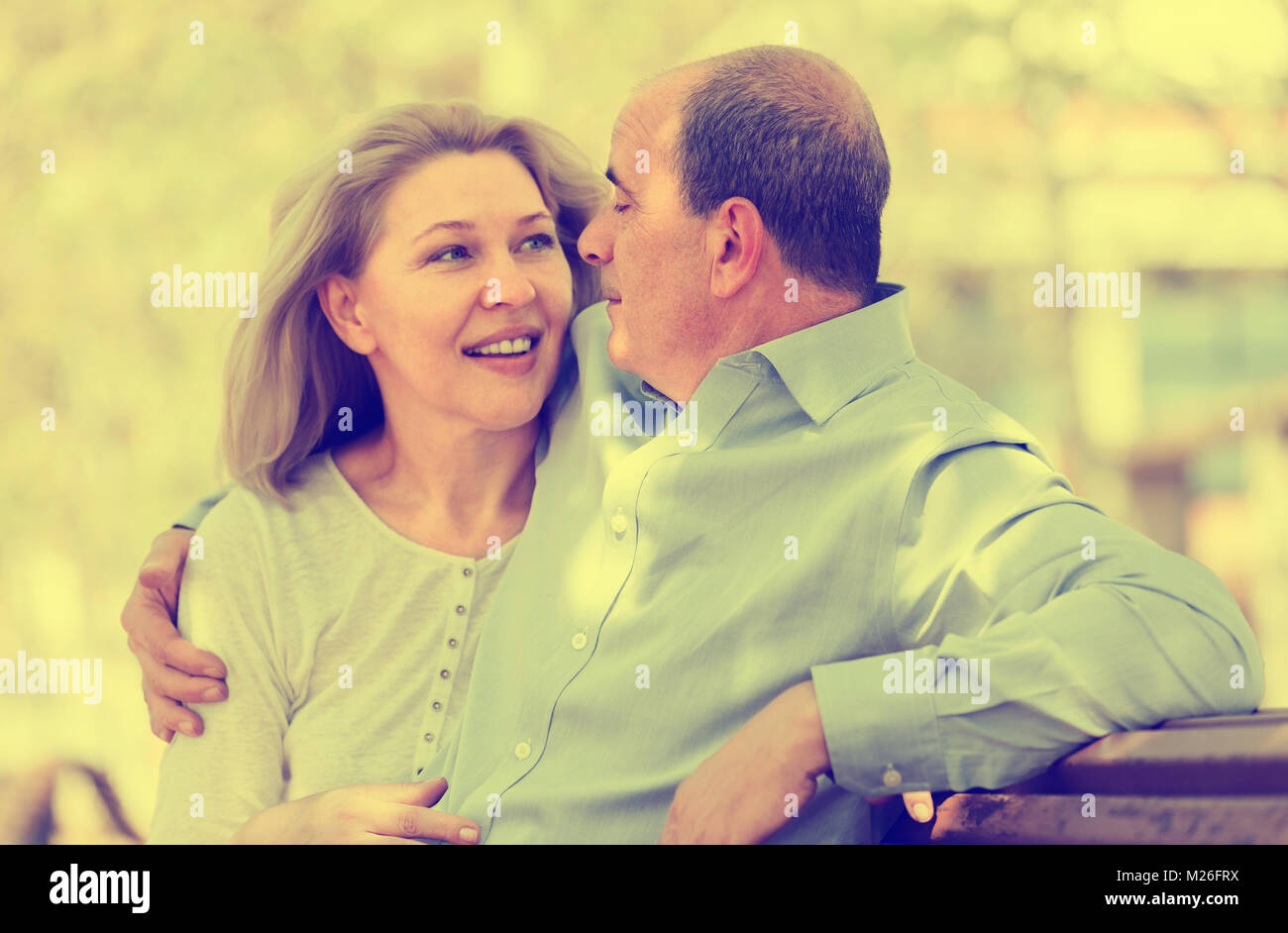 happy elderly couple hugging on a bench in park Stock Photo - Alamy