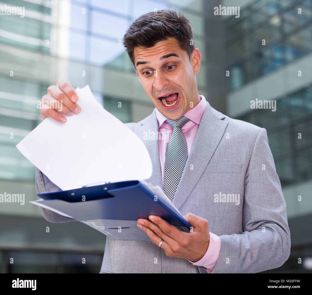 Surprised and shocked businessman reading documents on plant background ...