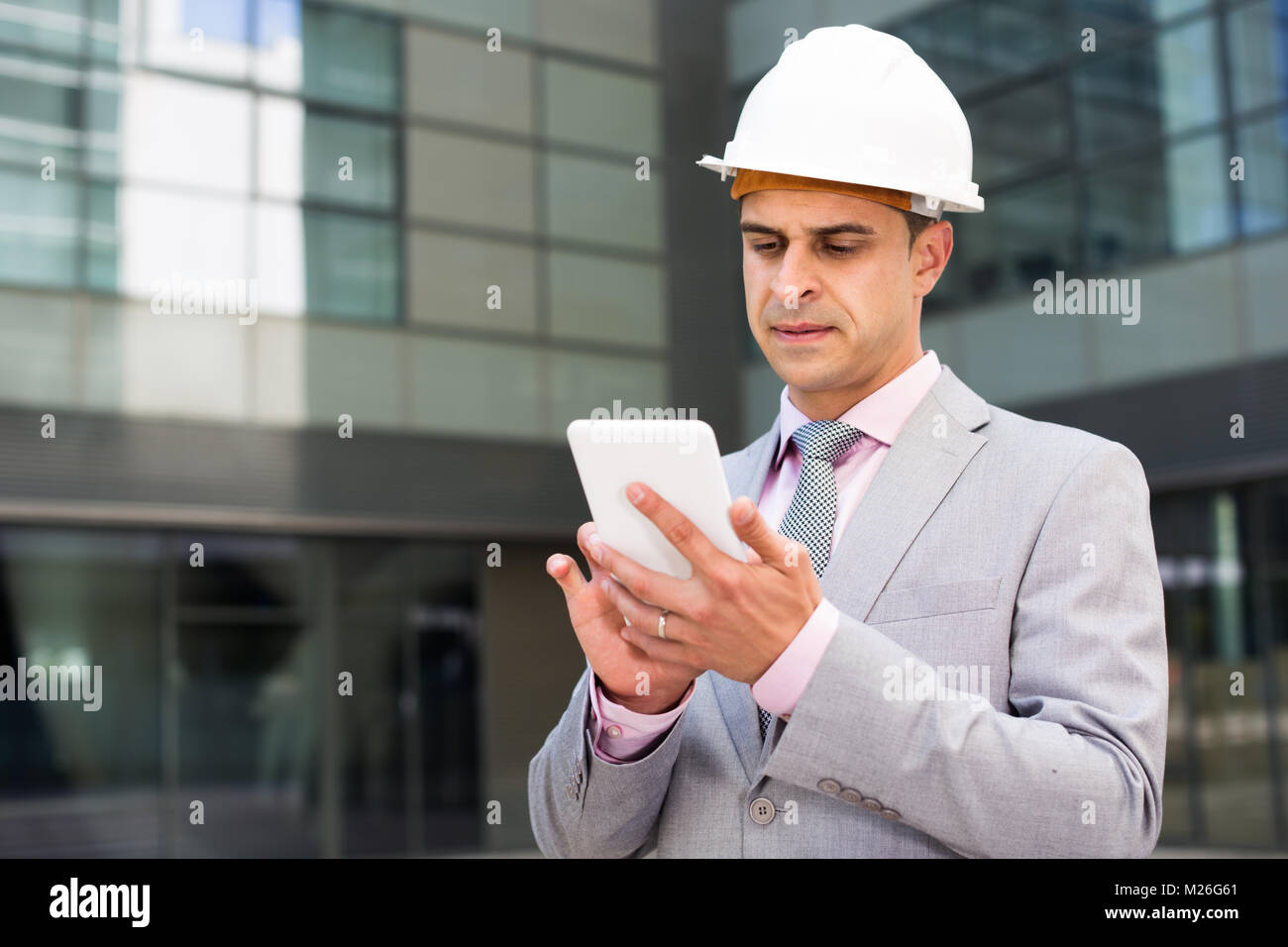 Confident young businessman standing on factory background and using cell phone Stock Photo - Alamy
