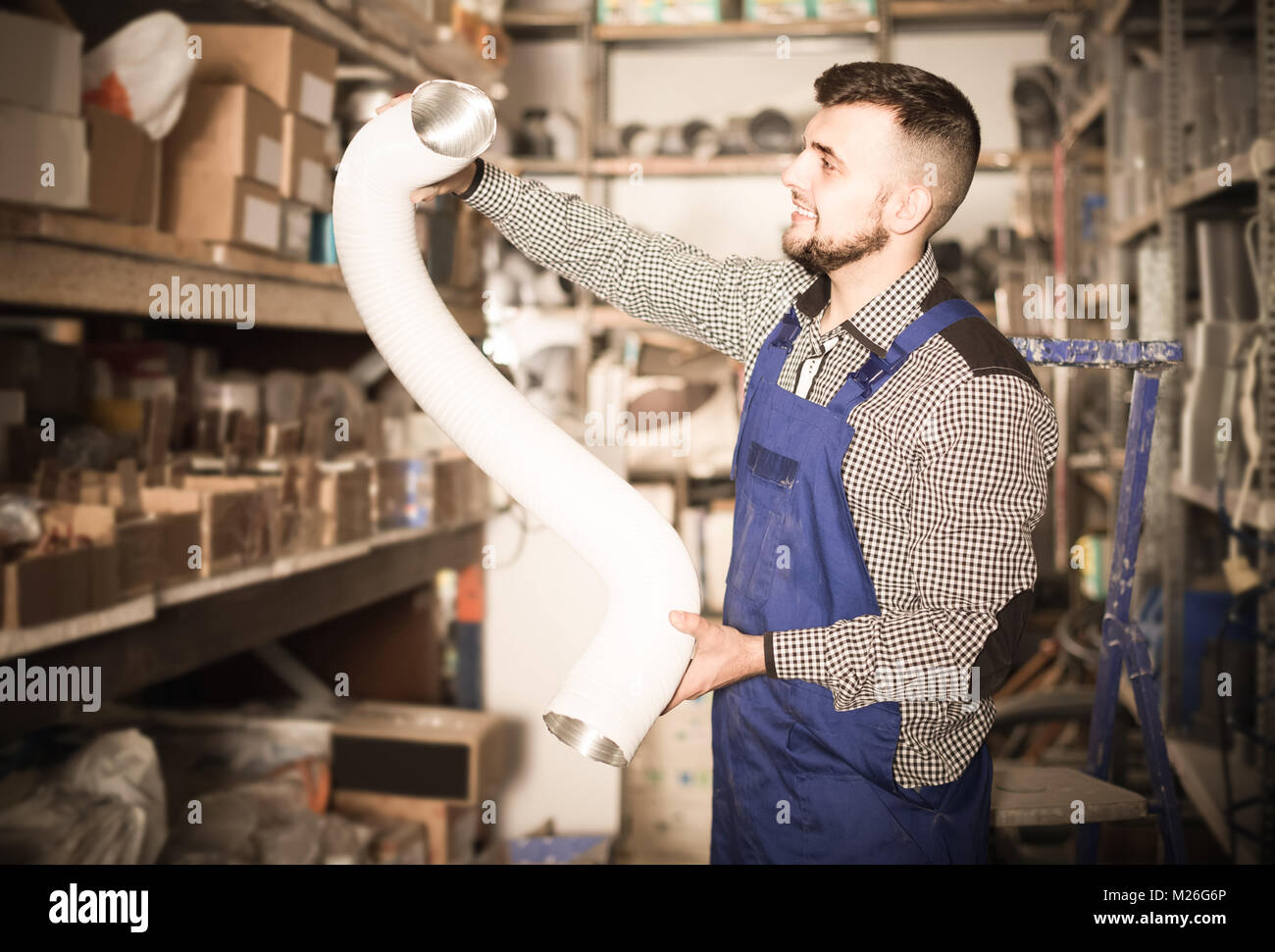 Young spanish worker choosing flexible aluminum pipe for ventilation in ...