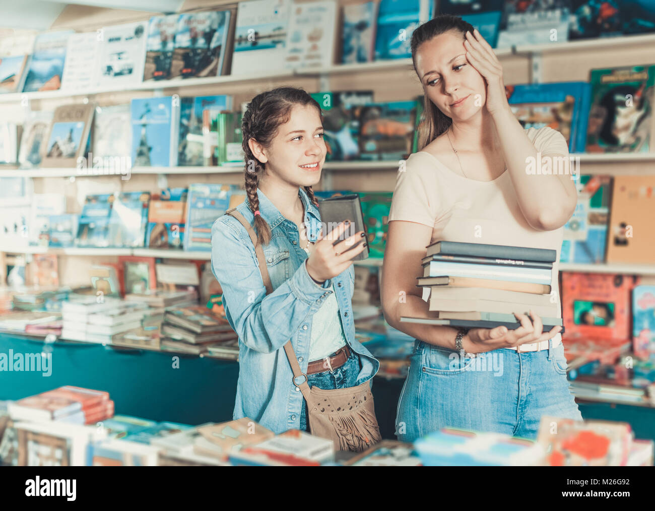 Attractive girl picking textbooks with telephone in bookstore Stock ...