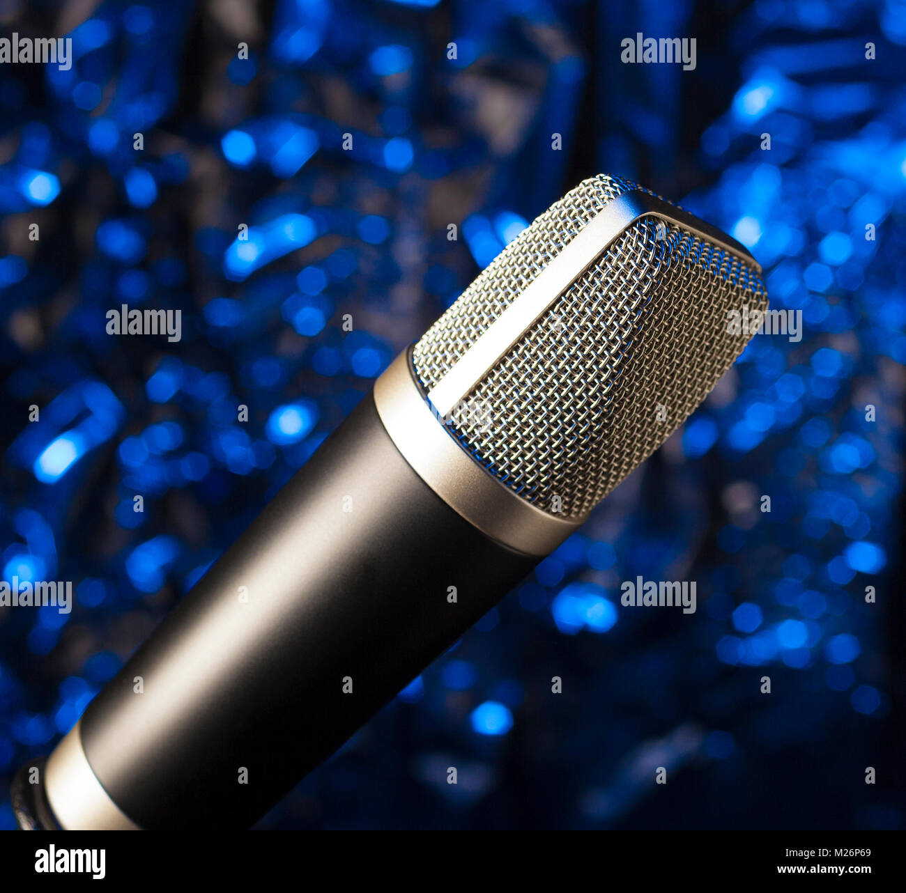 Silver meshed microphone that is on a blue background Stock Photo - Alamy