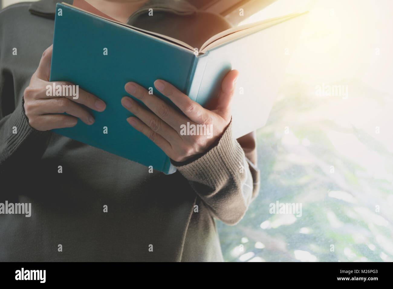 Woman holding blue book for read on nature background Stock Photo - Alamy