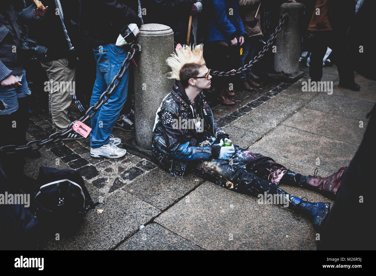 A young punk rocker is chilling and takes a break with a cold beer at a ...
