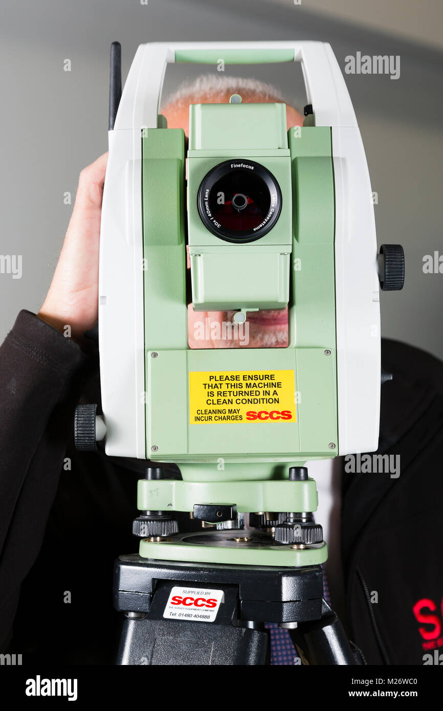 A man looks through a theodolite mounted on a tripod Stock Photo - Alamy