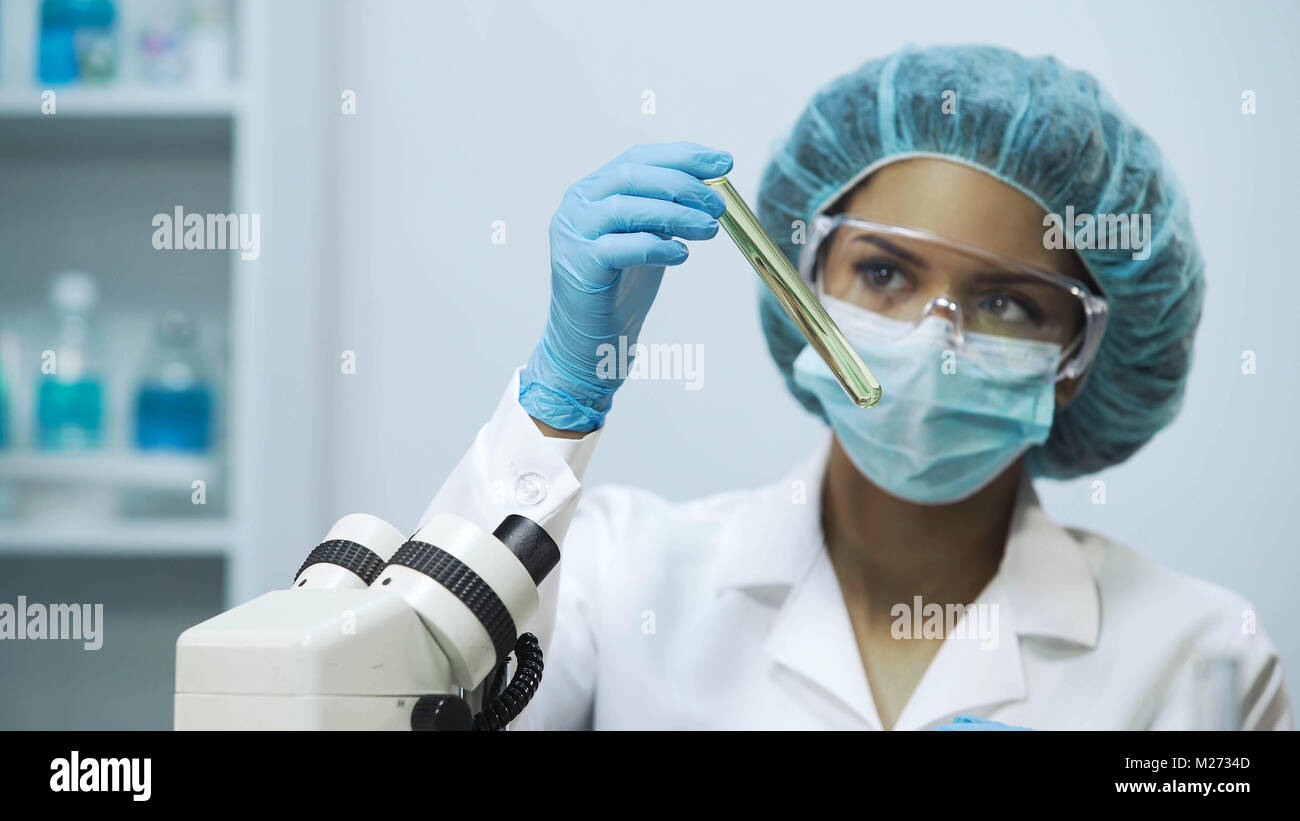 Professional bacteriologist checking liquid transparency in medical ...