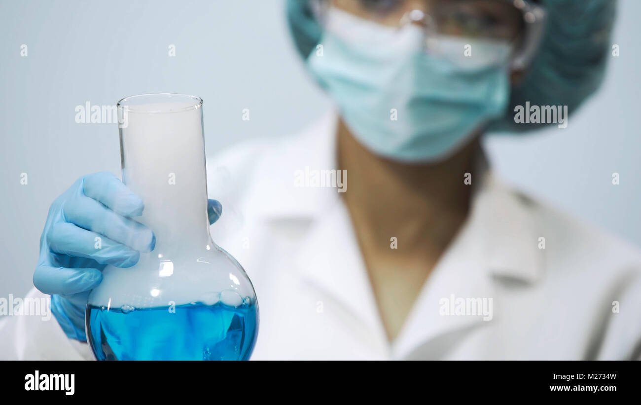 Demonstration of chemical reaction, woman holding flask with ...
