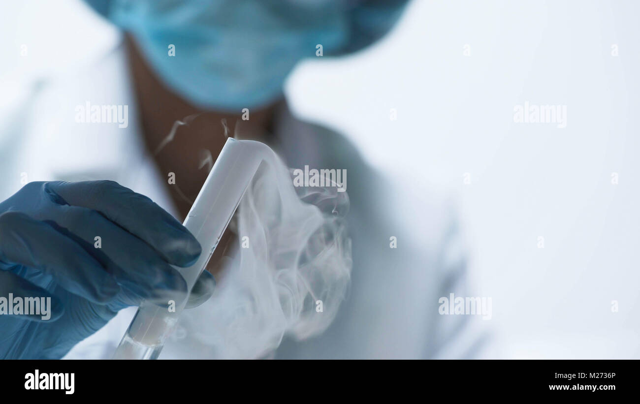 Chemical experiment, researcher holding test tube with boiling fuming ...
