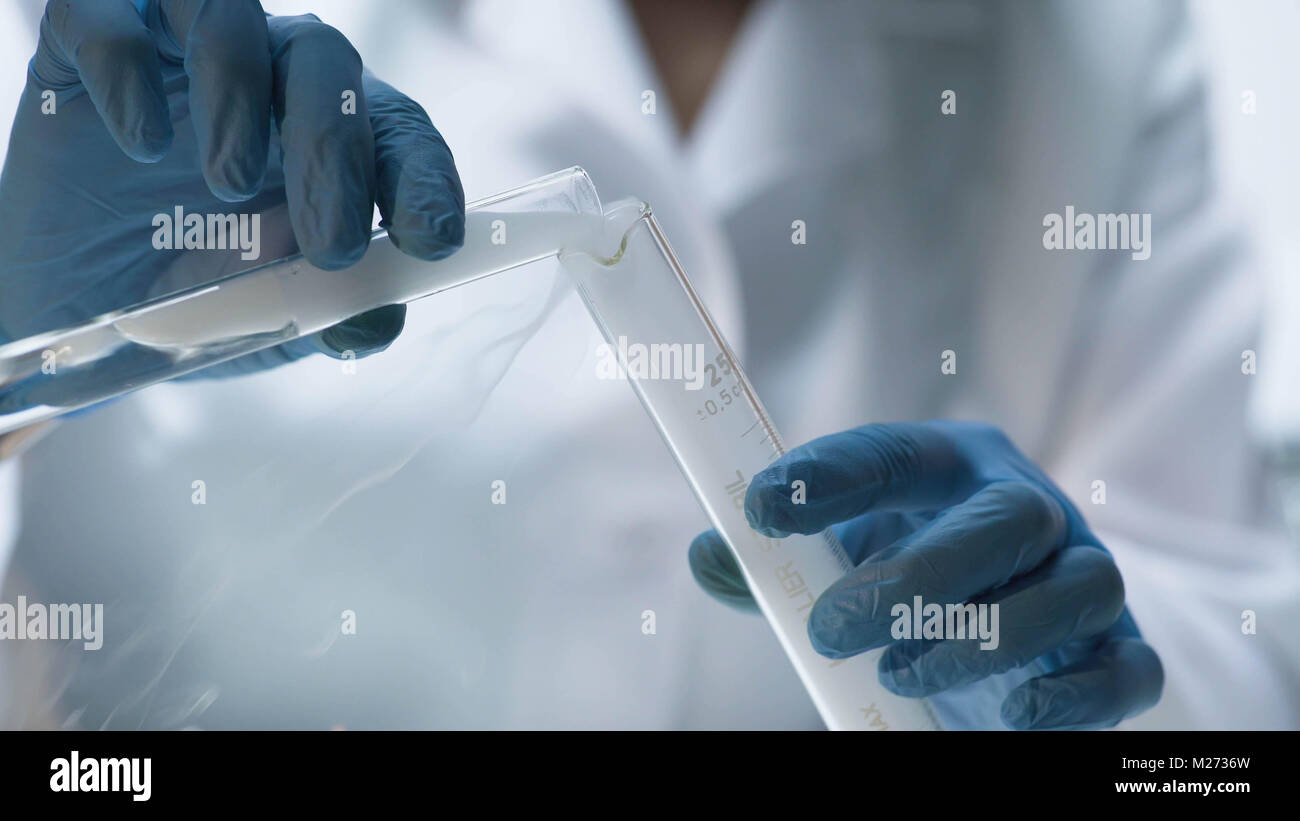 Chemical test, biochemist pouring evaporating liquid into the tube ...