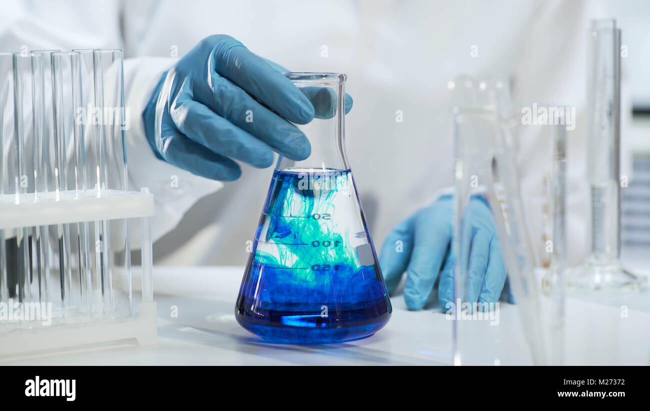 View of conical flask with liquid changing color into blue ...