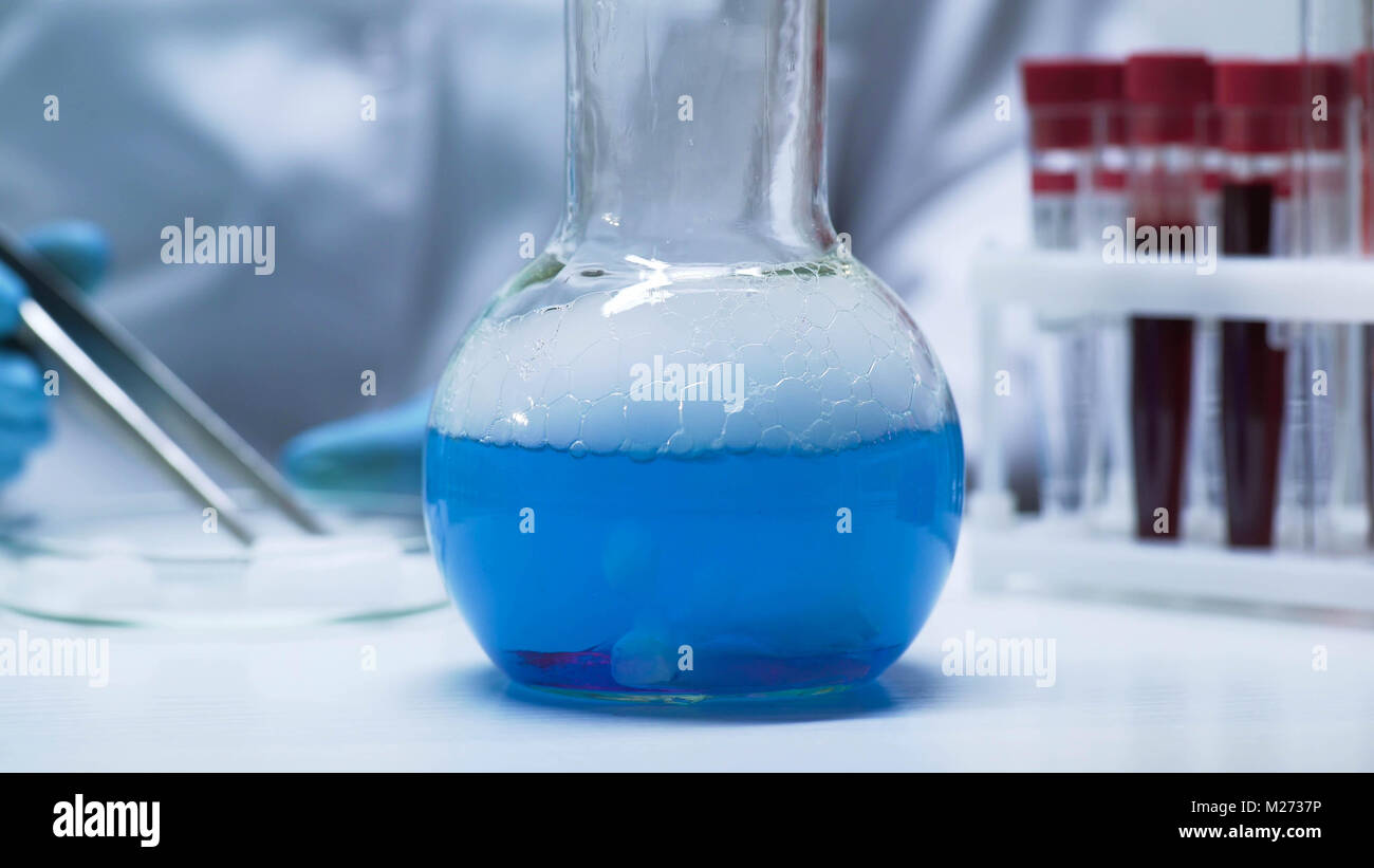Chemical flask with blue boiling liquid standing on the table at ...