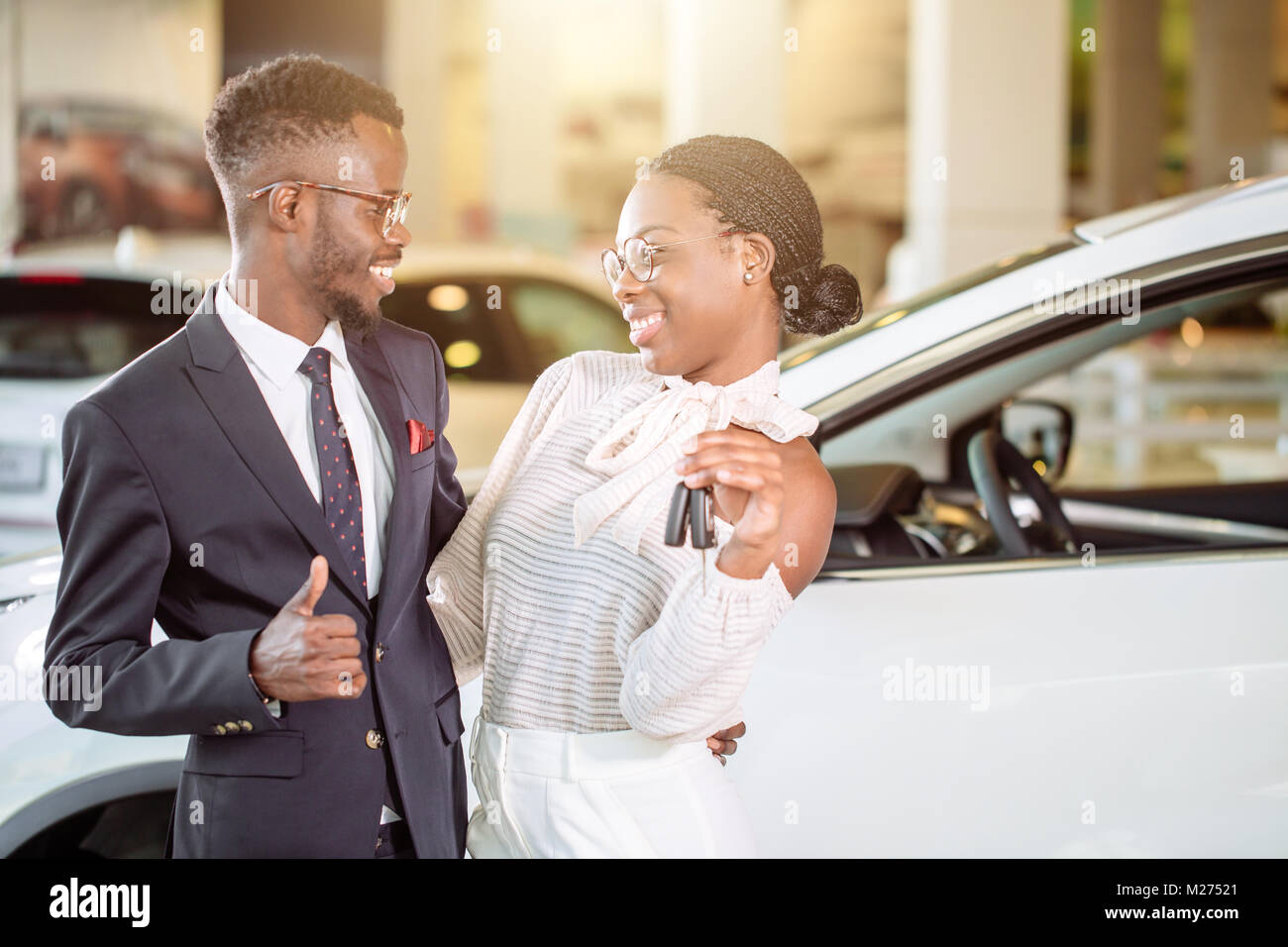 Visiting car dealership. couple holding key of their new car, looking ...